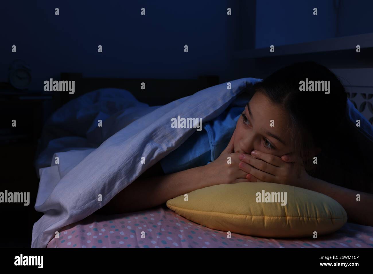 Afraid girl with pillow under duvet on bed at night Stock Photo - Alamy