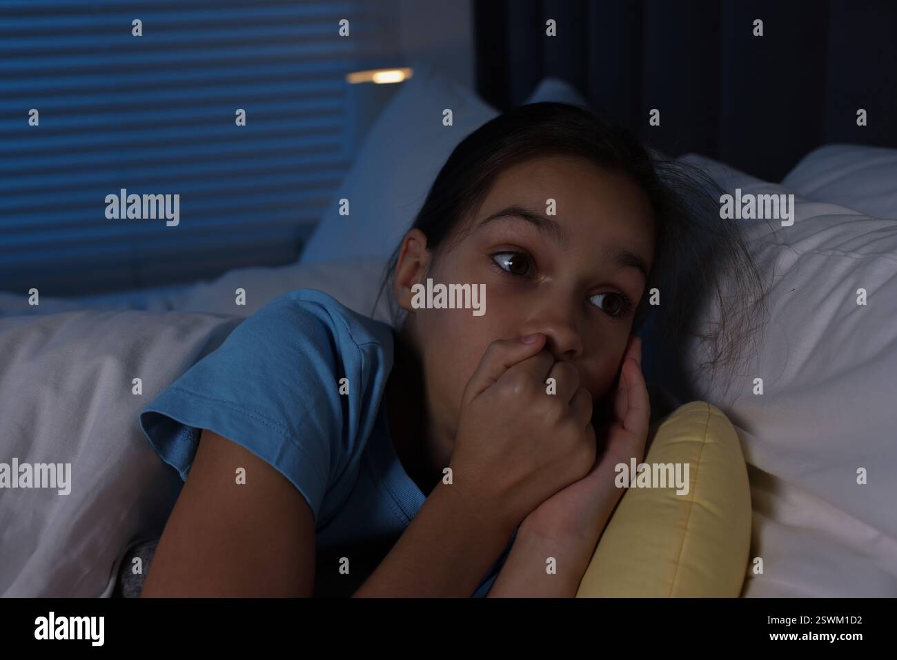 Fearful girl lying on bed at night Stock Photo - Alamy