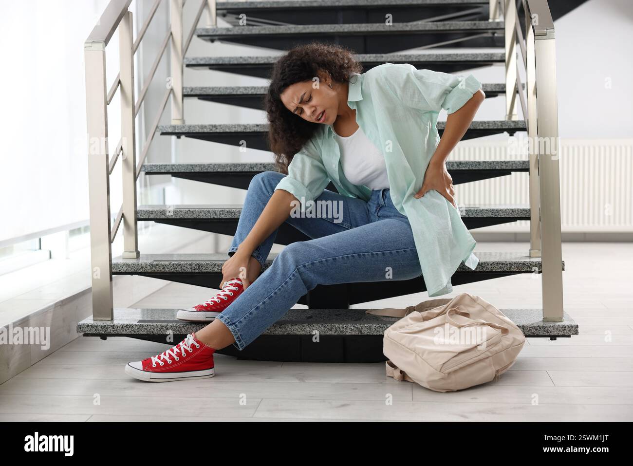 Woman with injured back on stairs in building after fall. Dangerous ...