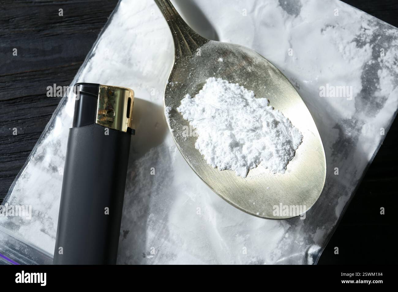 Drug addiction. Plastic bag with powder, spoon and cigarette lighter on ...