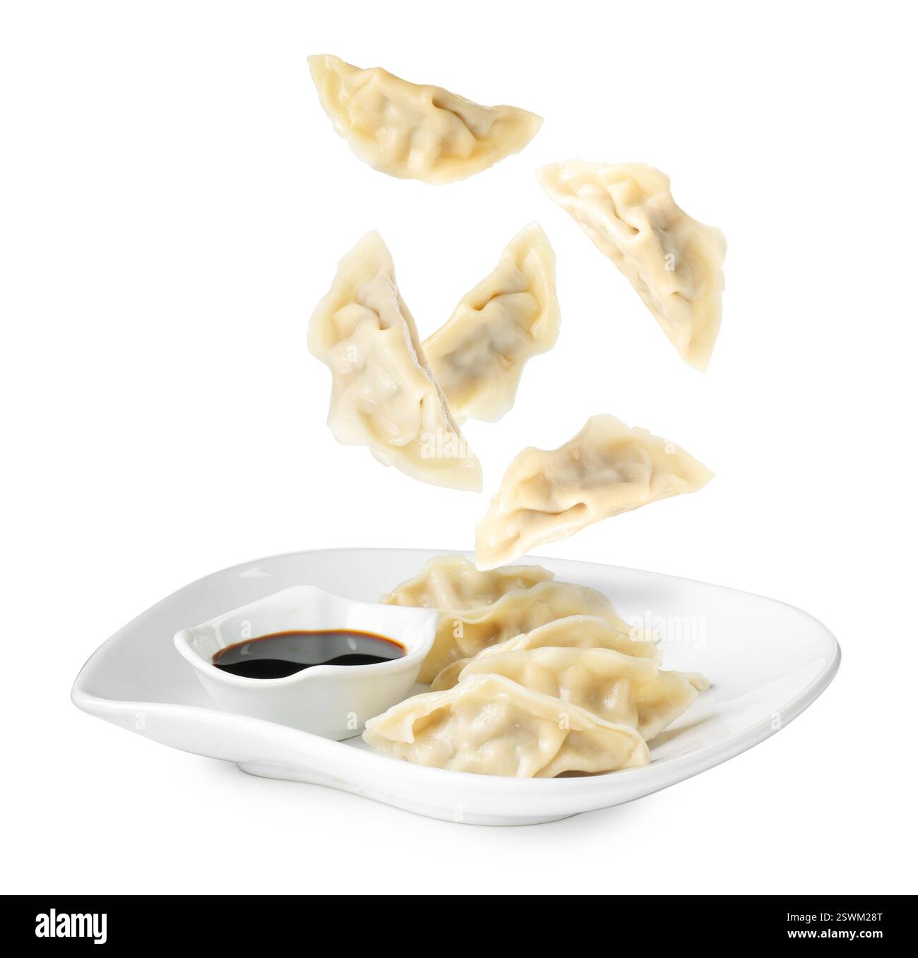 Tasty boiled gyoza (dumplings) falling onto plate on white background ...