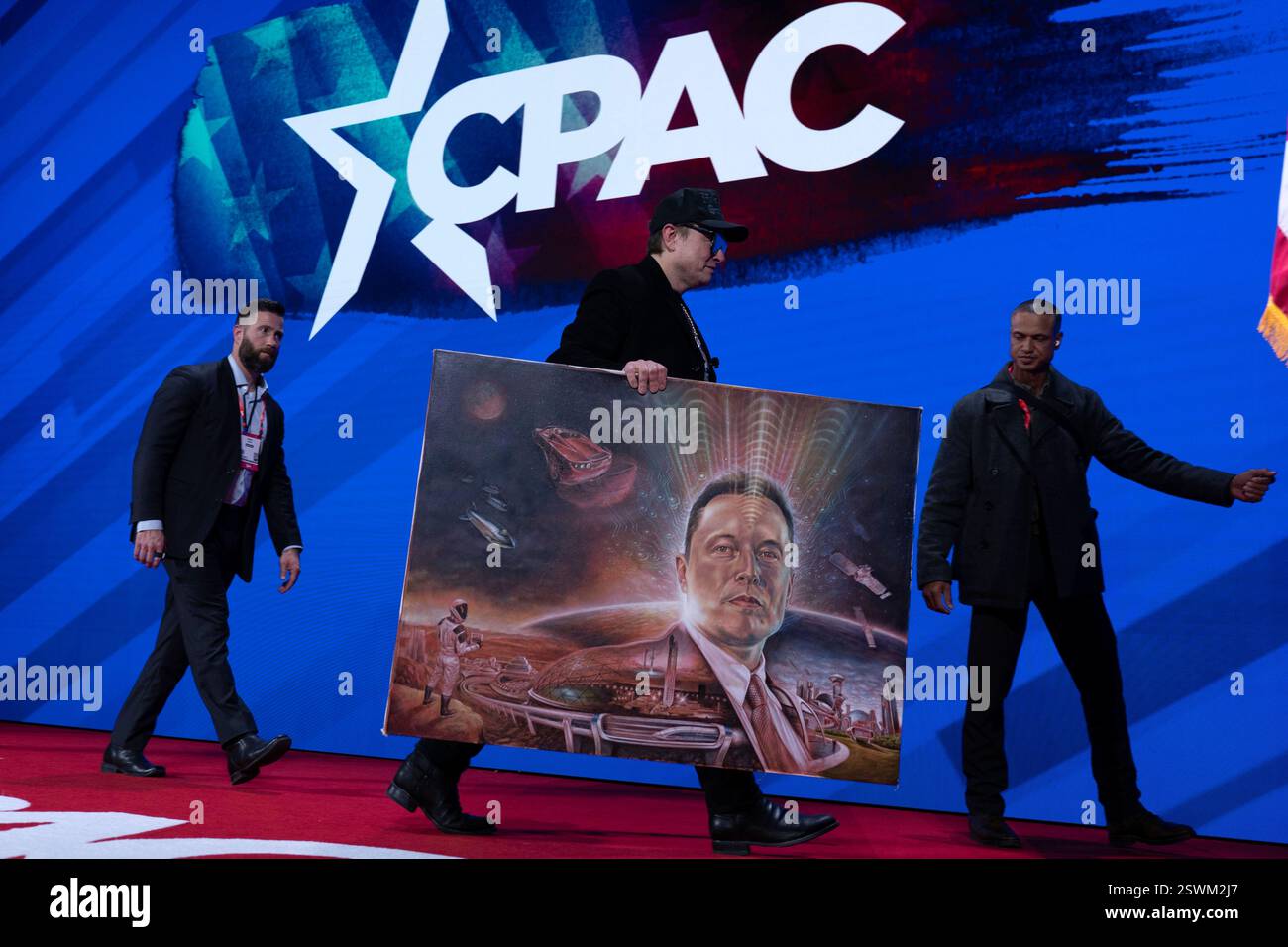 Elon Musk holds a painting after speaking at the Conservative Political ...