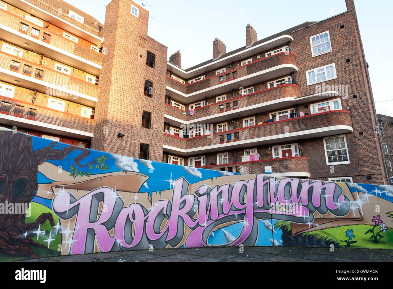 Graffiti mural of "Rockingham" on a wall beside a brick apartment ...
