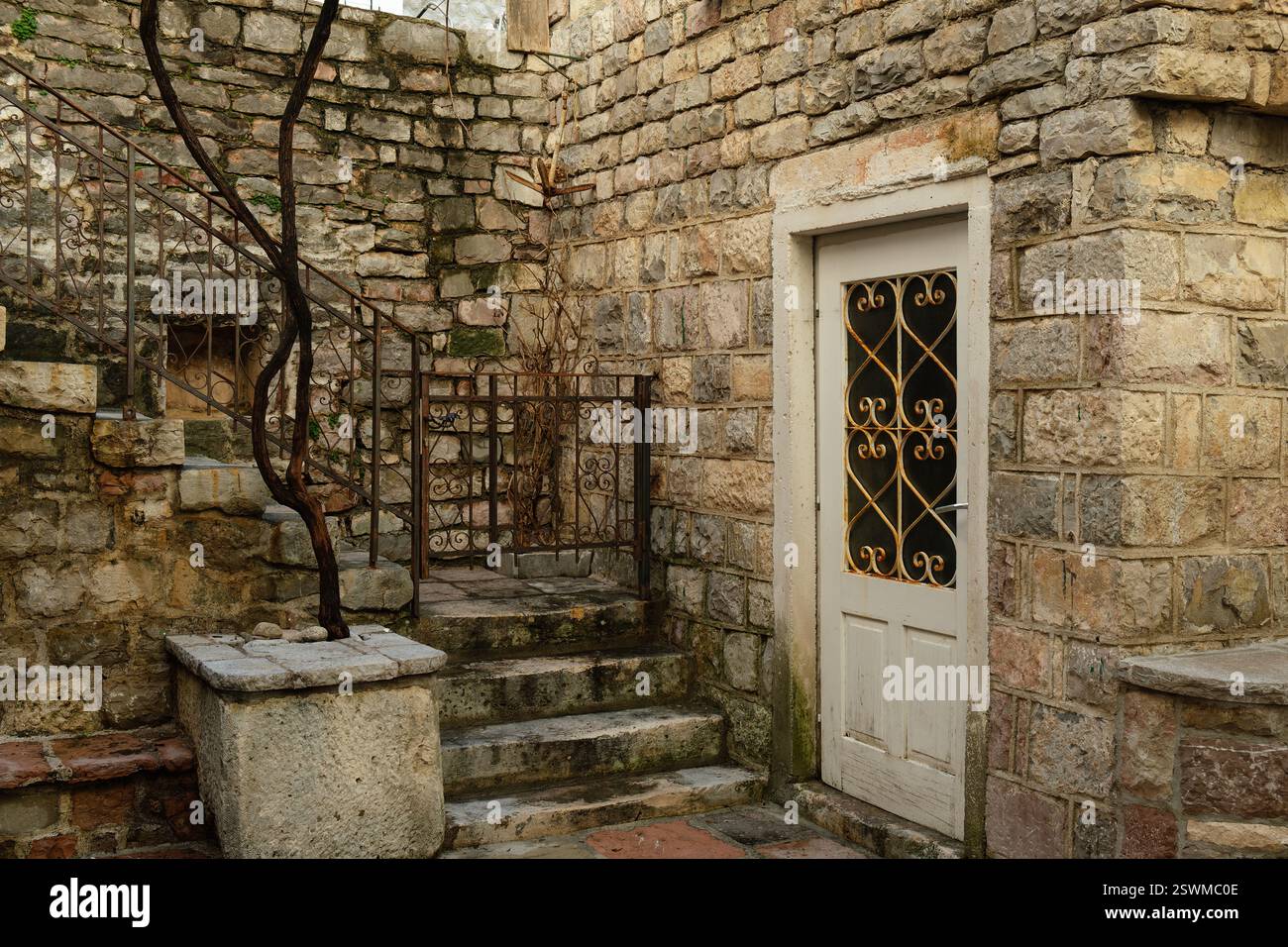 Old Mediterranean stone courtyard with a rustic wooden door, shady cozy ...