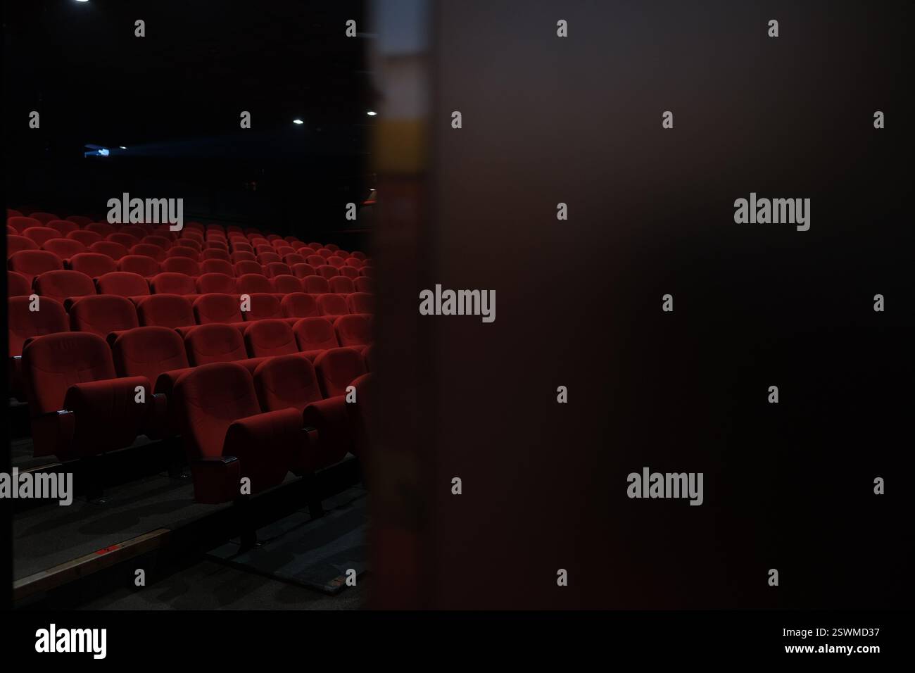 Rows of empty red theater seats offer a glimpse into a darkened ...