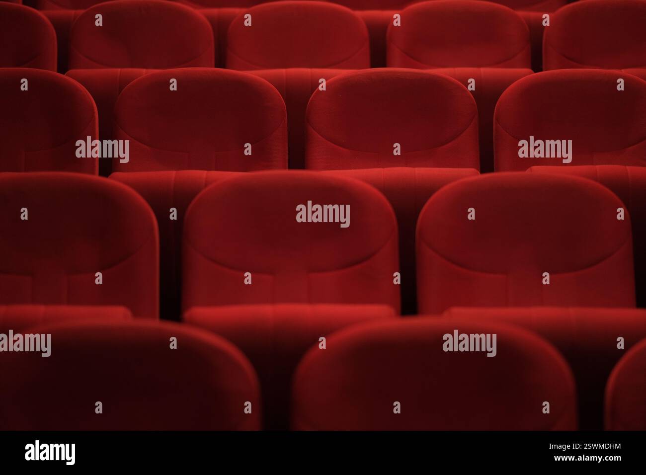 Rows of red cushioned seats arranged in a pattern invite an audience to ...