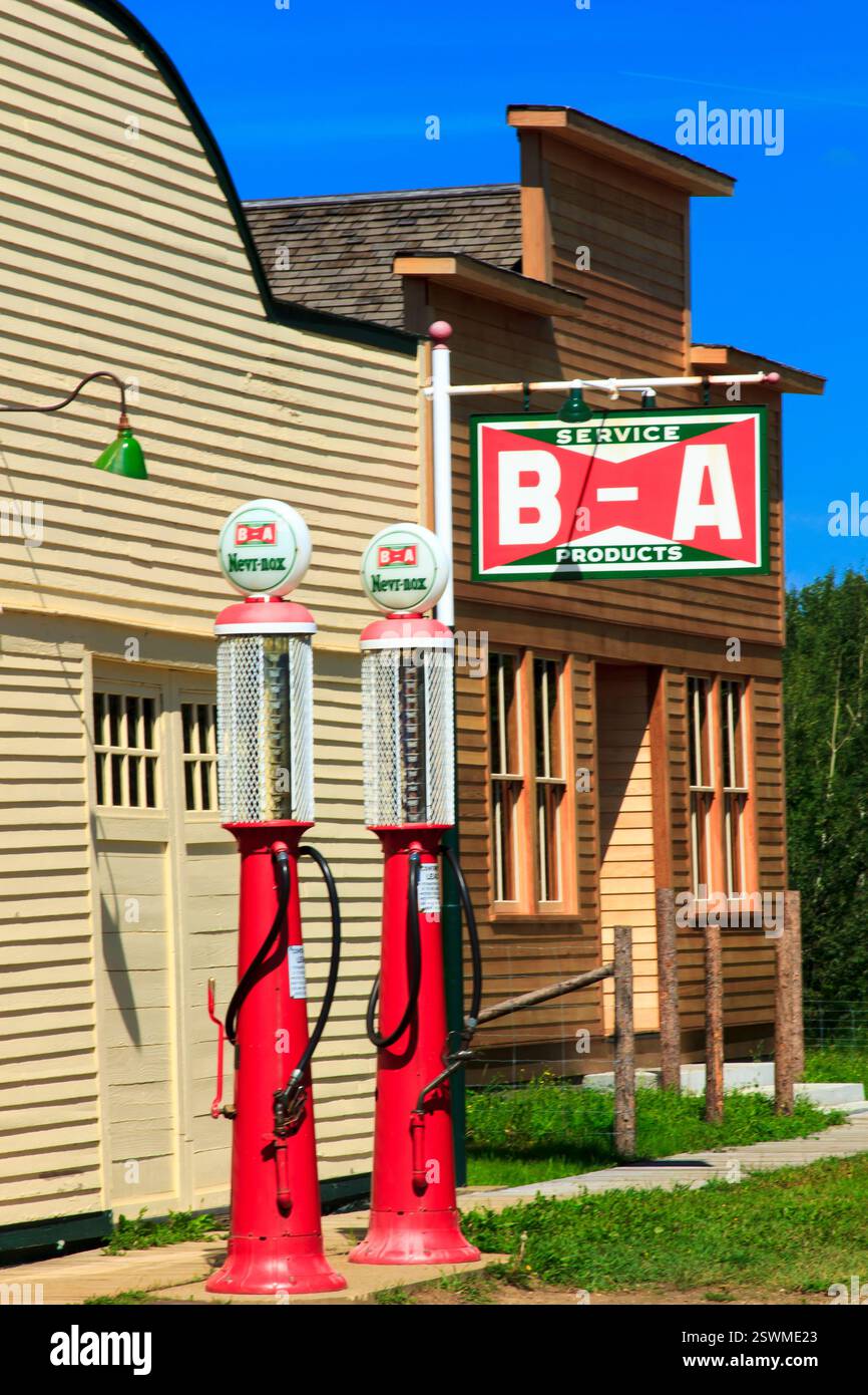 Two red gas pumps in front of a building with a sign that says B-A. The ...