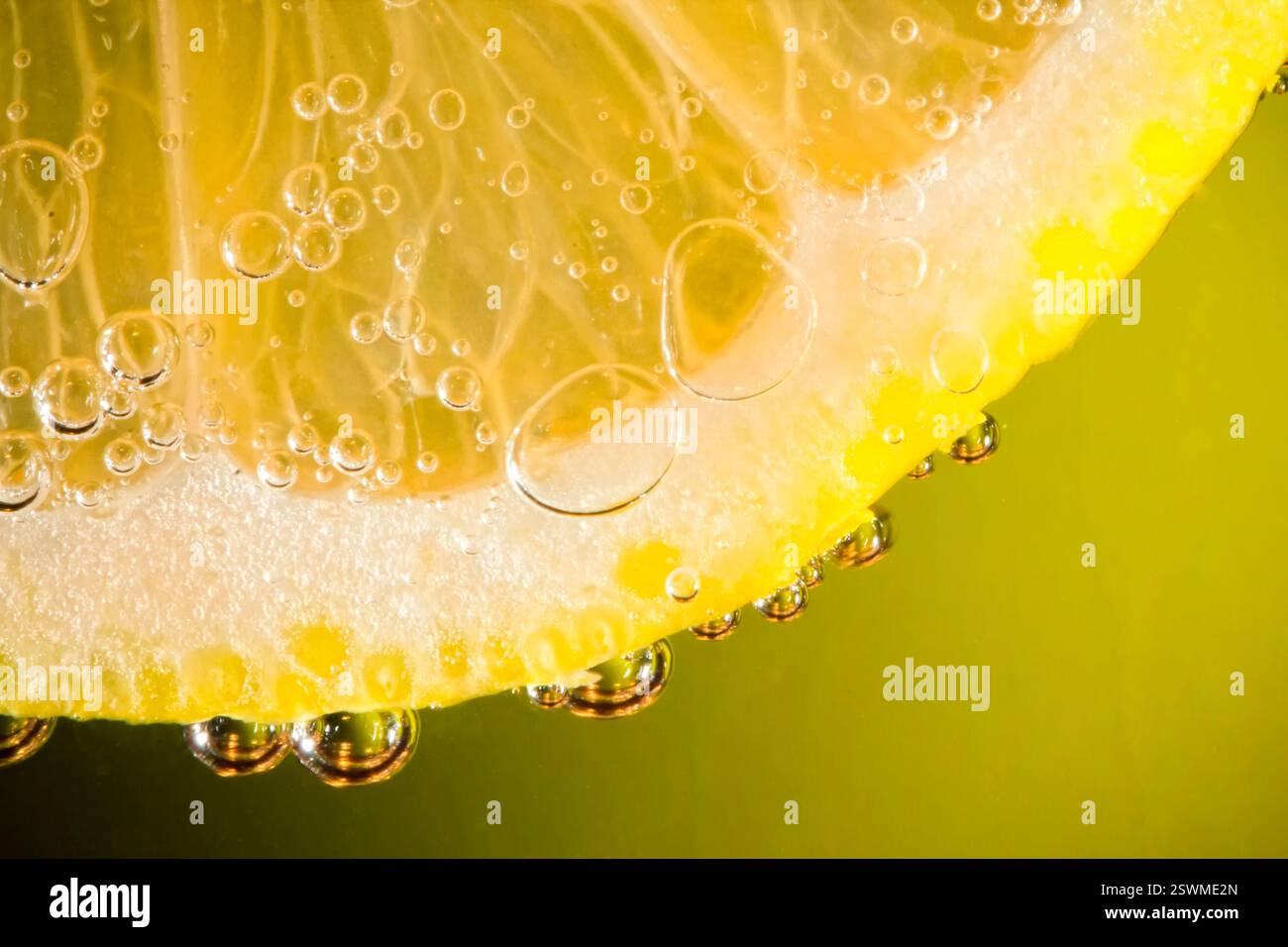 Slice of lemon with water droplets on it. The lemon is yellow and the water droplets are clear ...