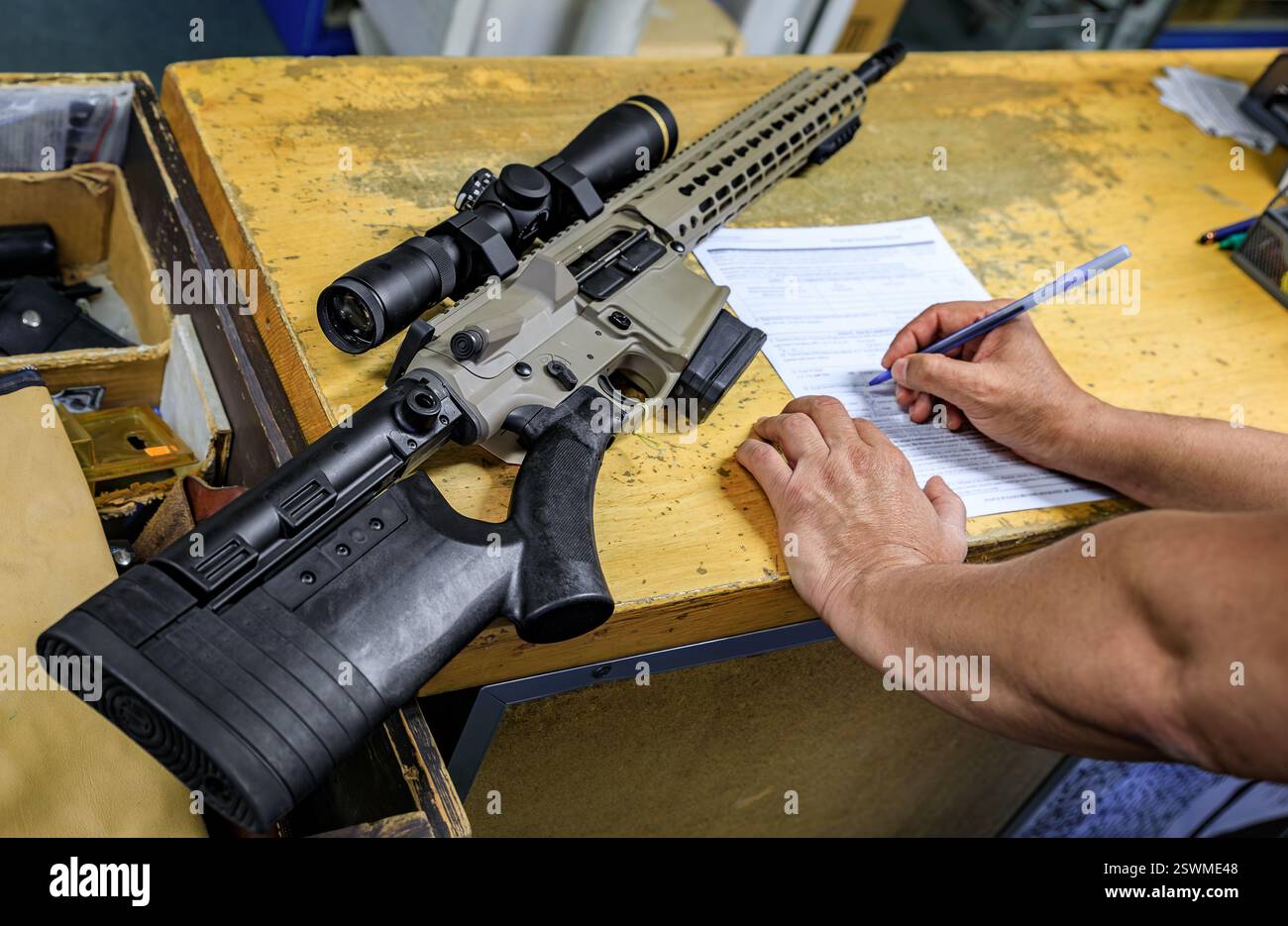California gun shop: male buyer signs the paperwork beside a modern AR ...