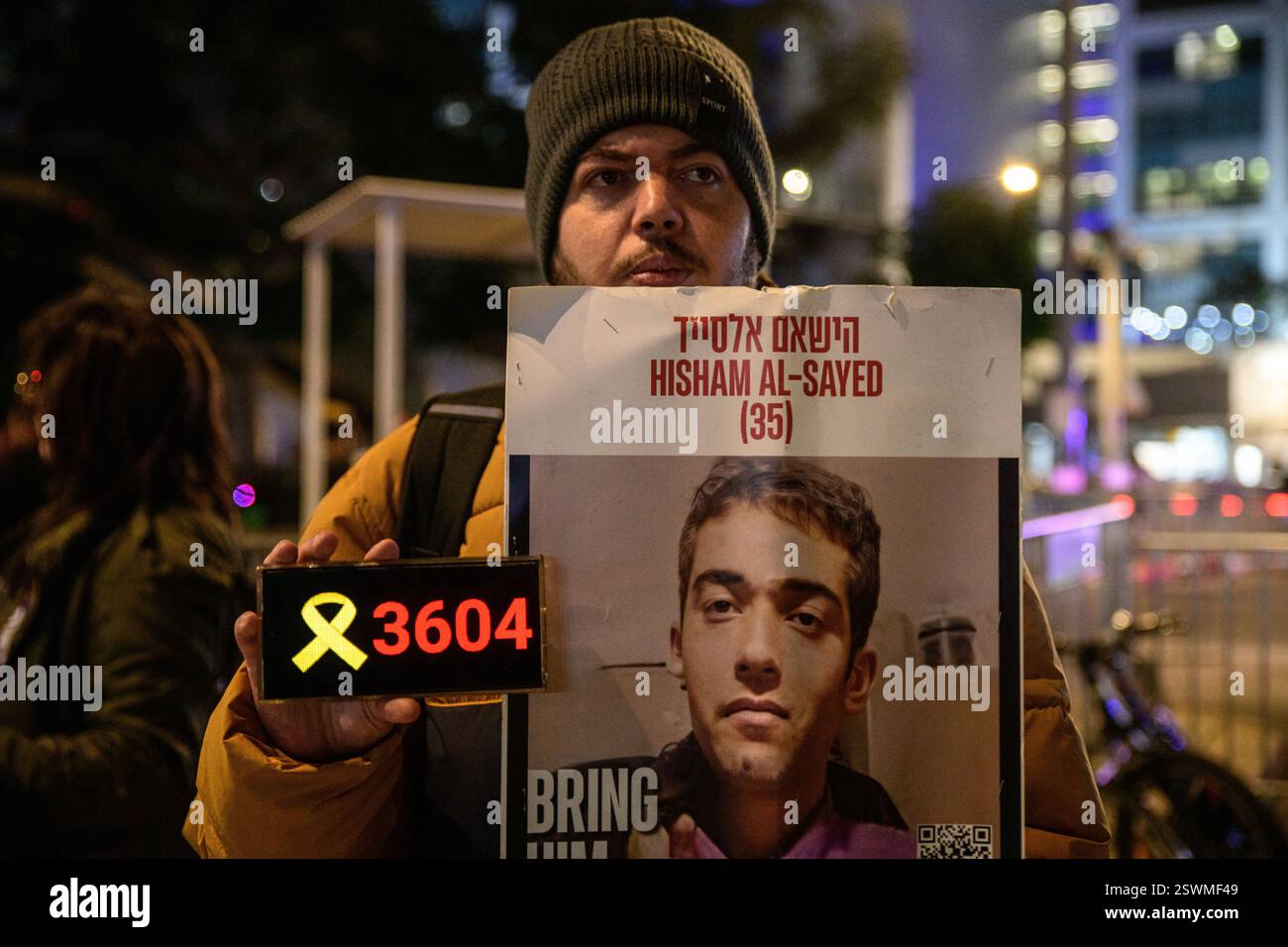 A protestor holds a portrait of Israeli hostage Hisham Al-Sayed and a ...