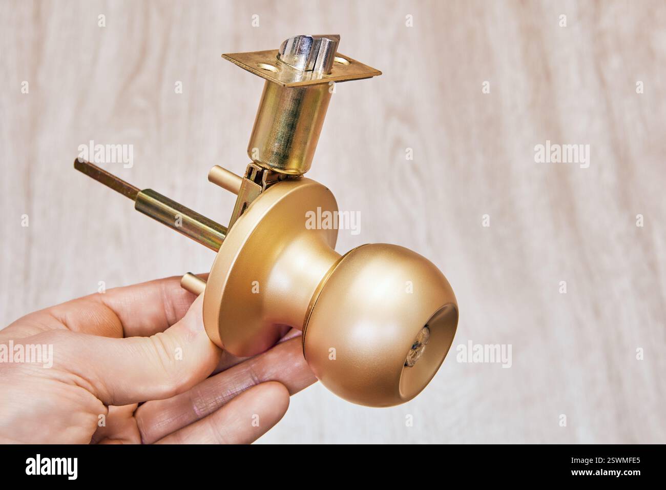 Tubular door latch assembly is being held, highlighting brass ...