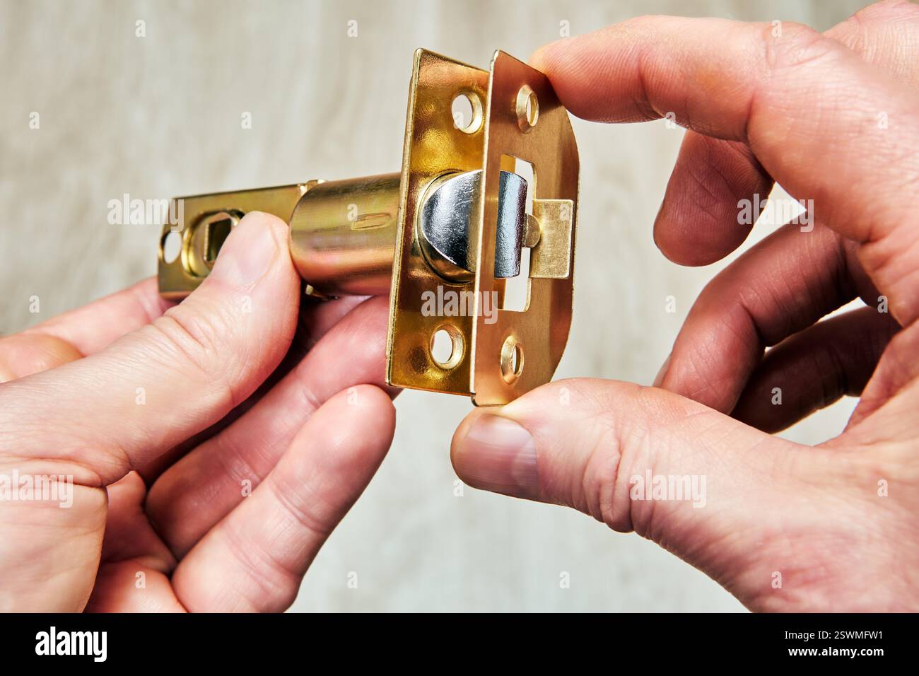 Hand holds new tubular door latch, showcasing its brass faceplate ...