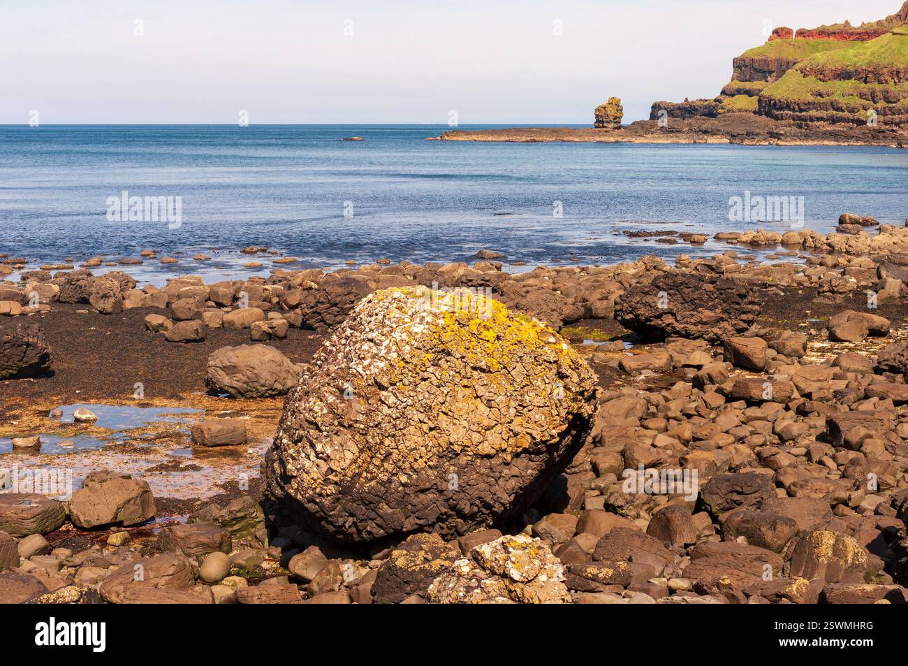 A large rock sits on a rocky shoreline, overlooking the ocean. The ...