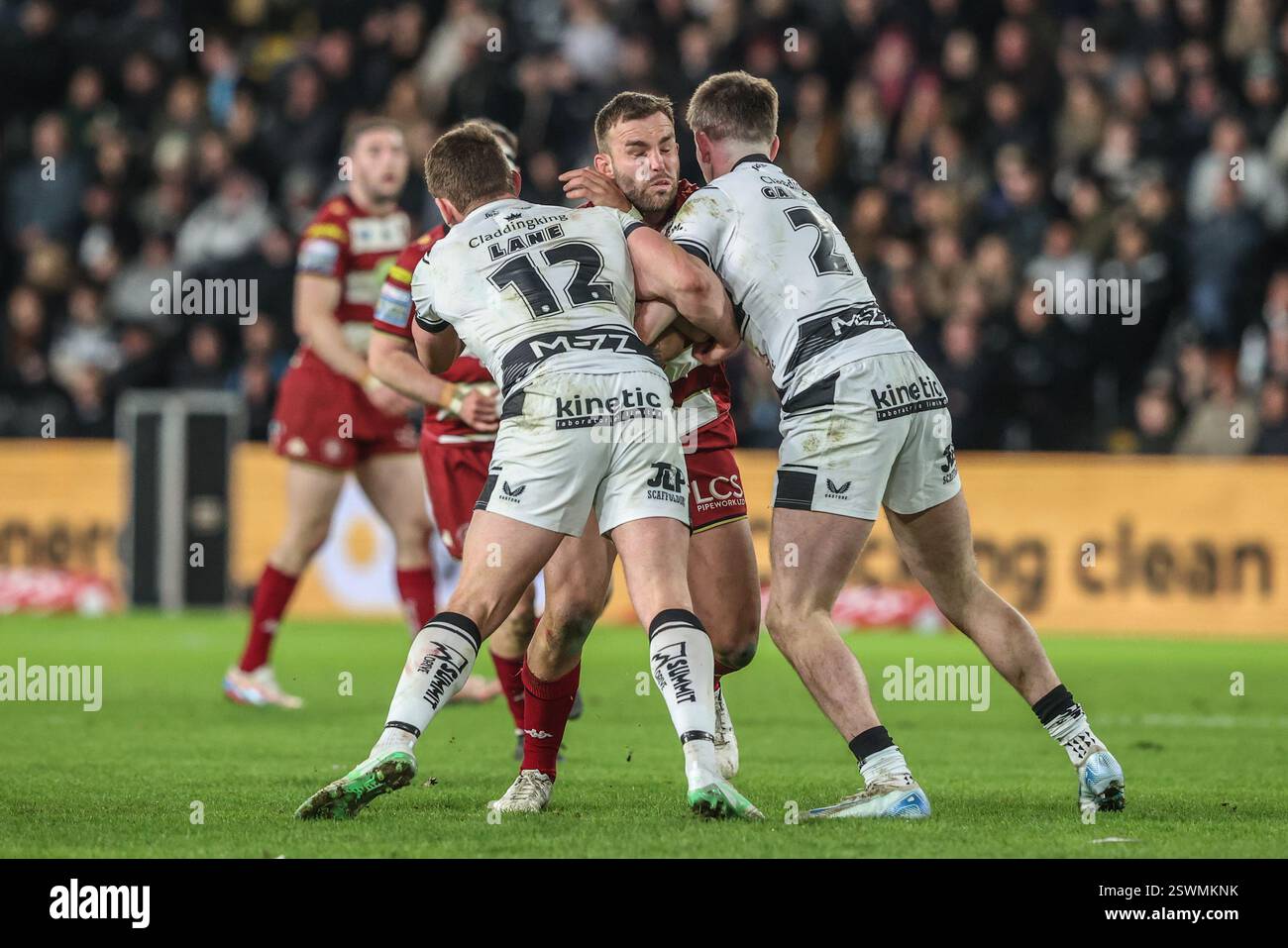 Kaide Ellis of Wigan Warriors is tackled by Jordan Lane of Hull FC and ...