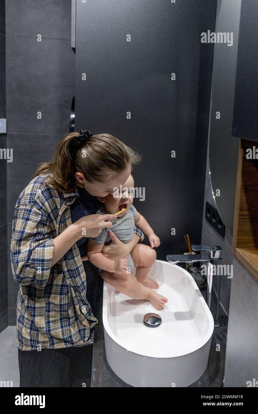 A woman is diligently brushing her teeth while simultaneously holding a ...
