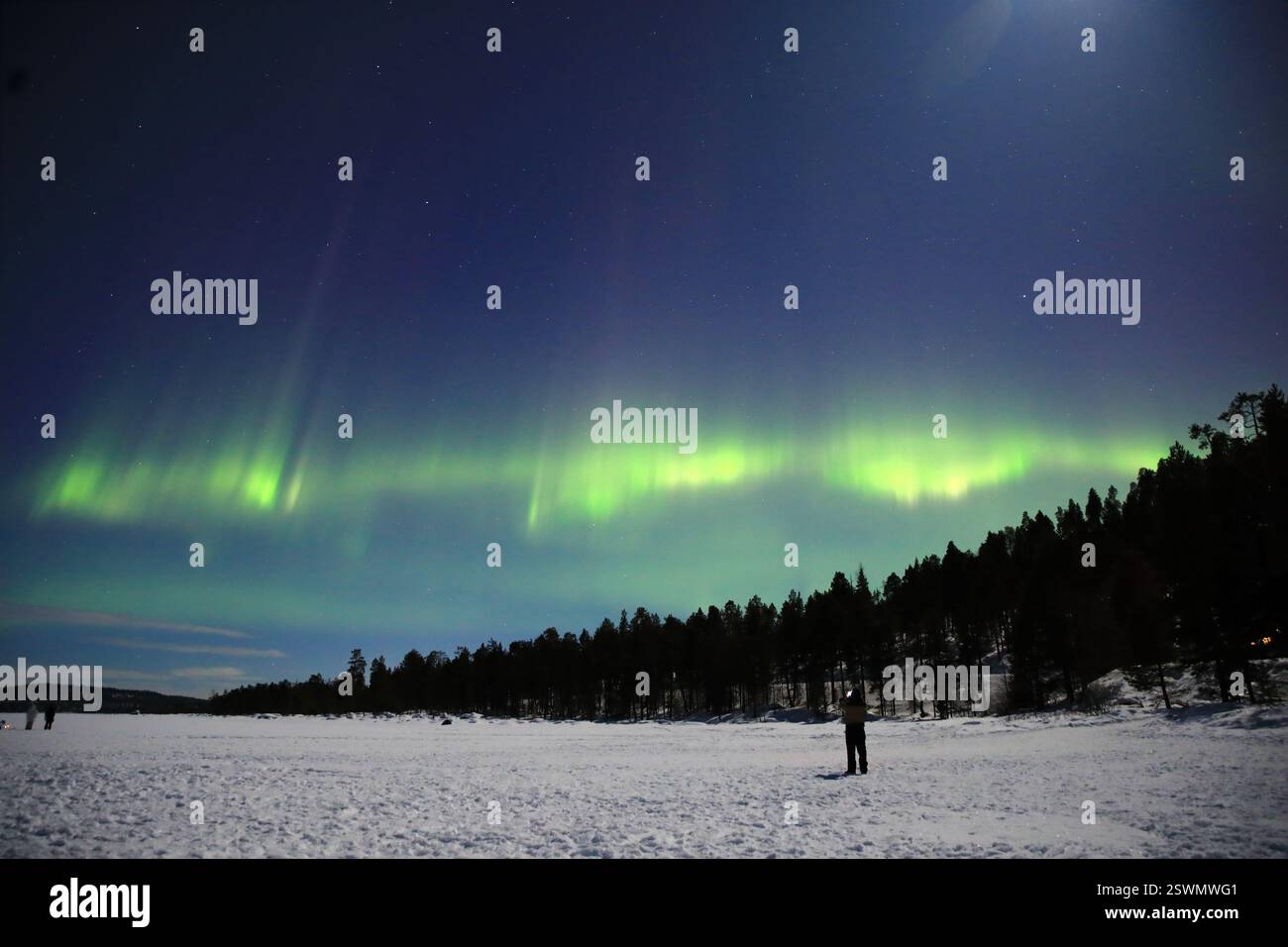 People observing the Aurora Borealis seen at lake Inari, Northern ...