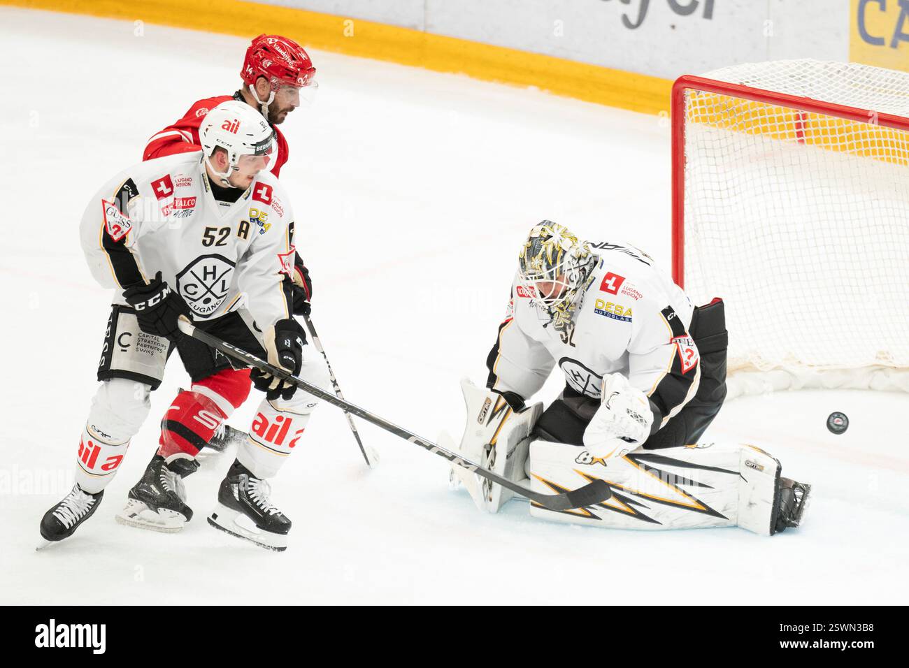 Lausanne, Switzerland. , . Adam Huska (goalkeeper) of Lugano HC #32 deflects the puck during ...