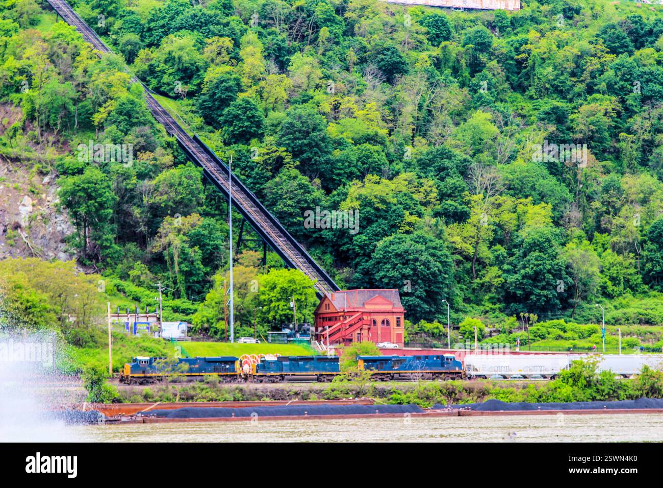 A train passes by the river adjacent to a historic funicular railway in ...