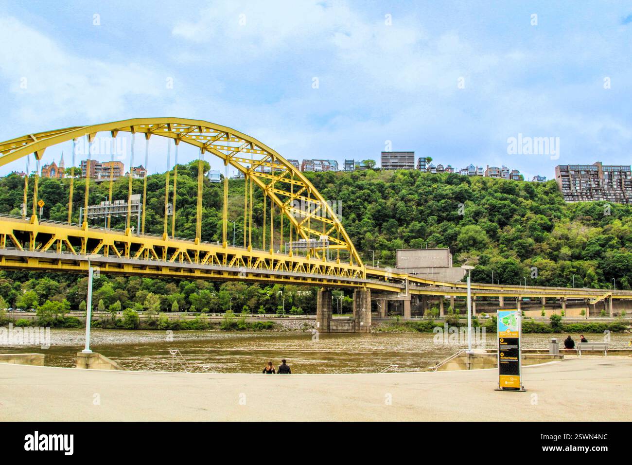 Visitors enjoy the waterfront while admiring the iconic yellow bridge ...