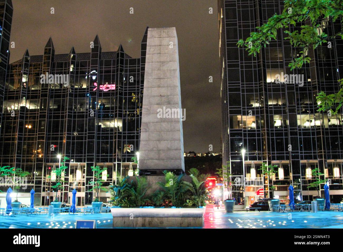 City lights illuminate a monument amid sleek buildings in downtown ...