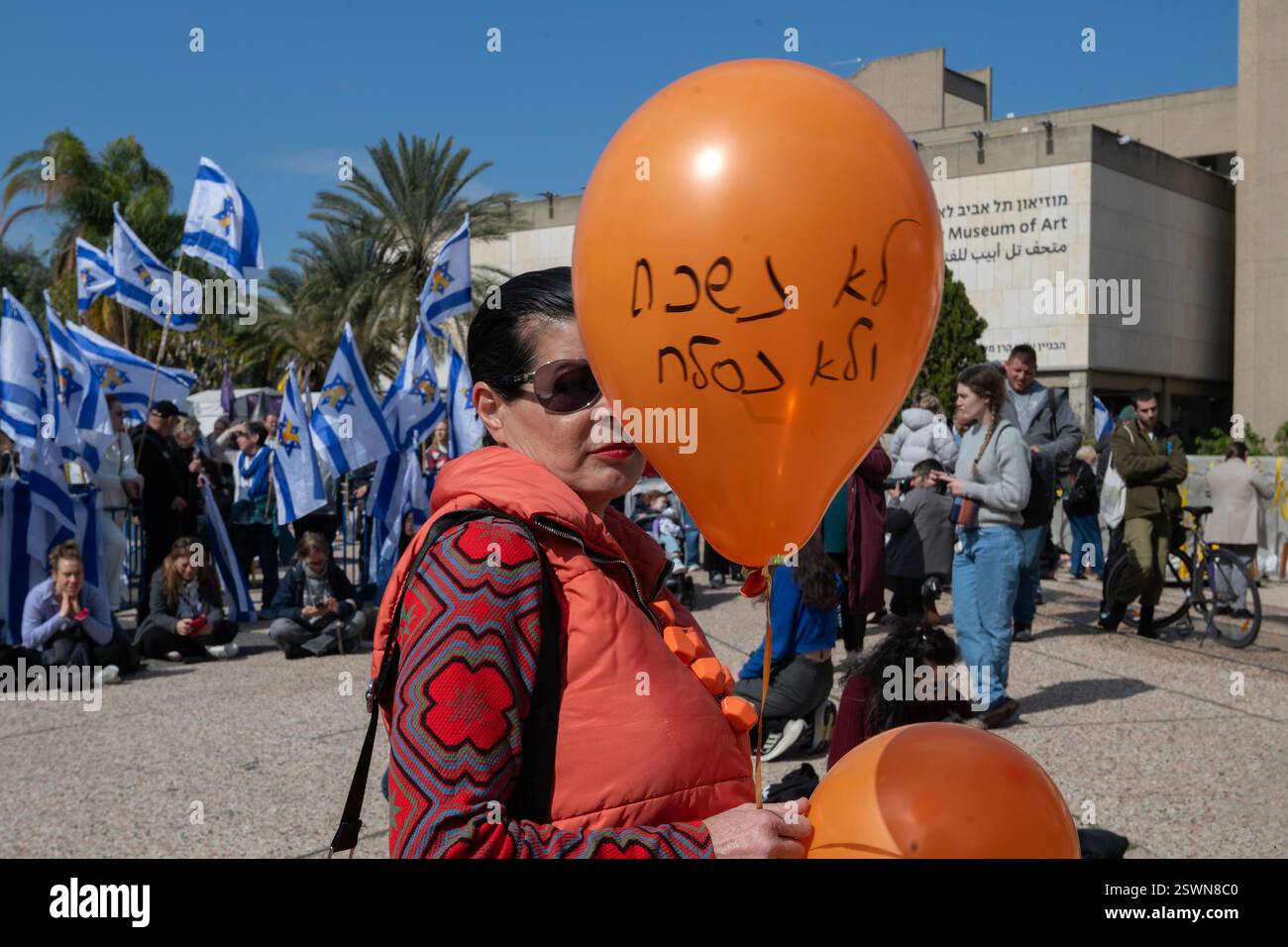 Tel Aviv, Israel. 20th Feb, 2025. A woman holds an orange balloon, the ...