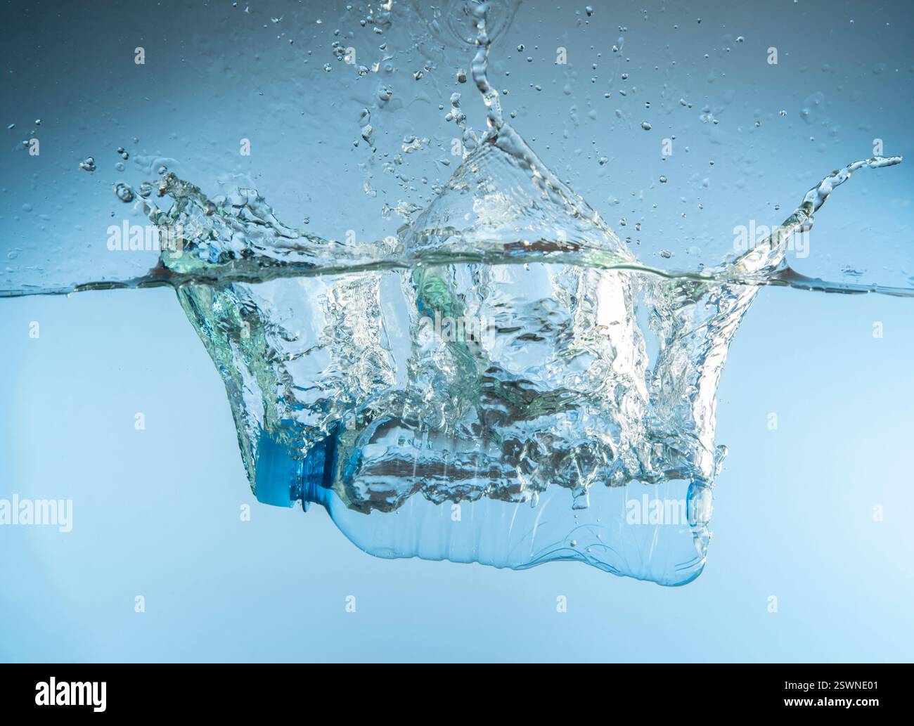 Front view of clear plastic bottle submerged in water causing a splash ...