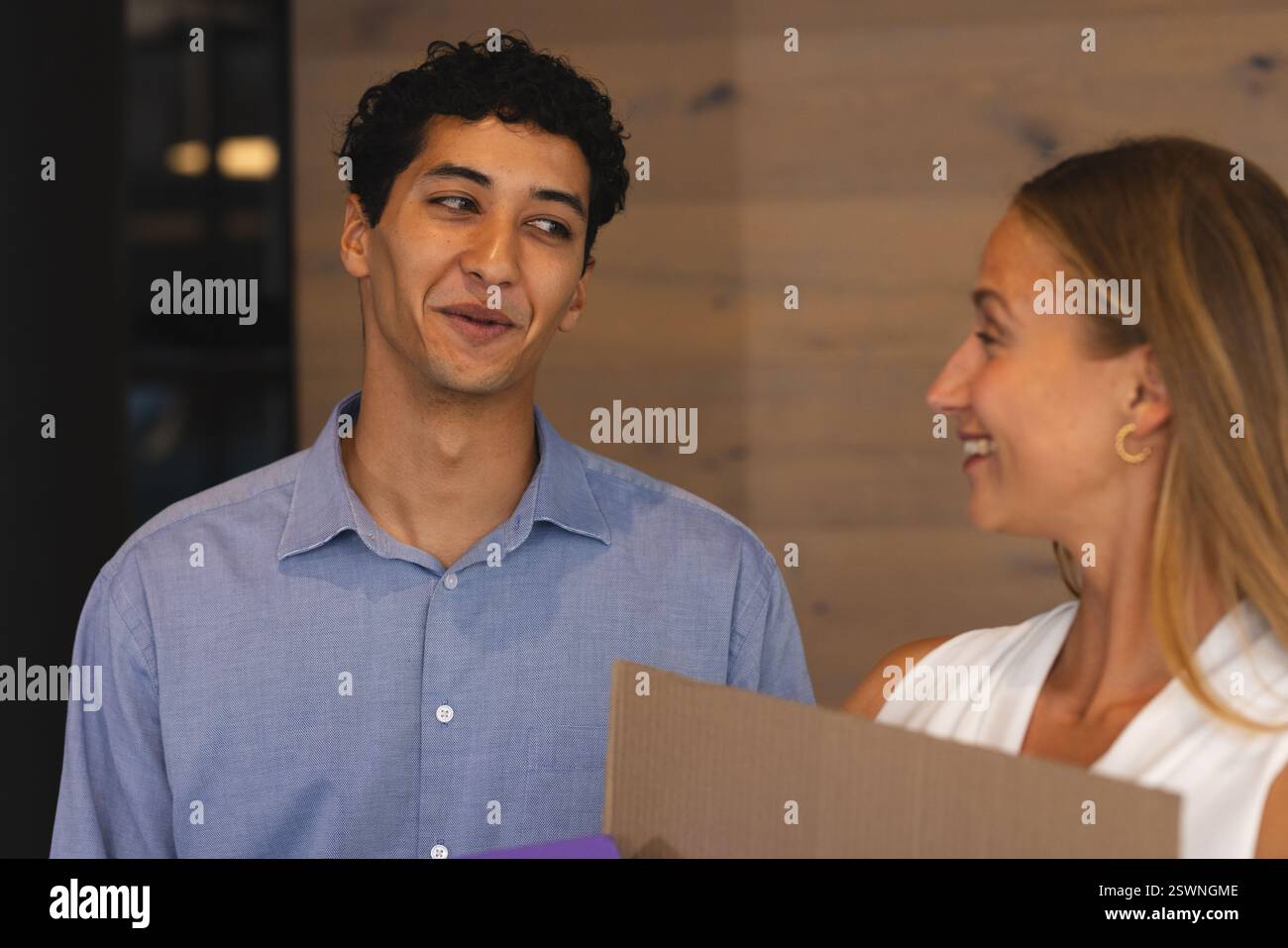 In office, diverse colleagues sharing light moment during business discussion at work desk ...