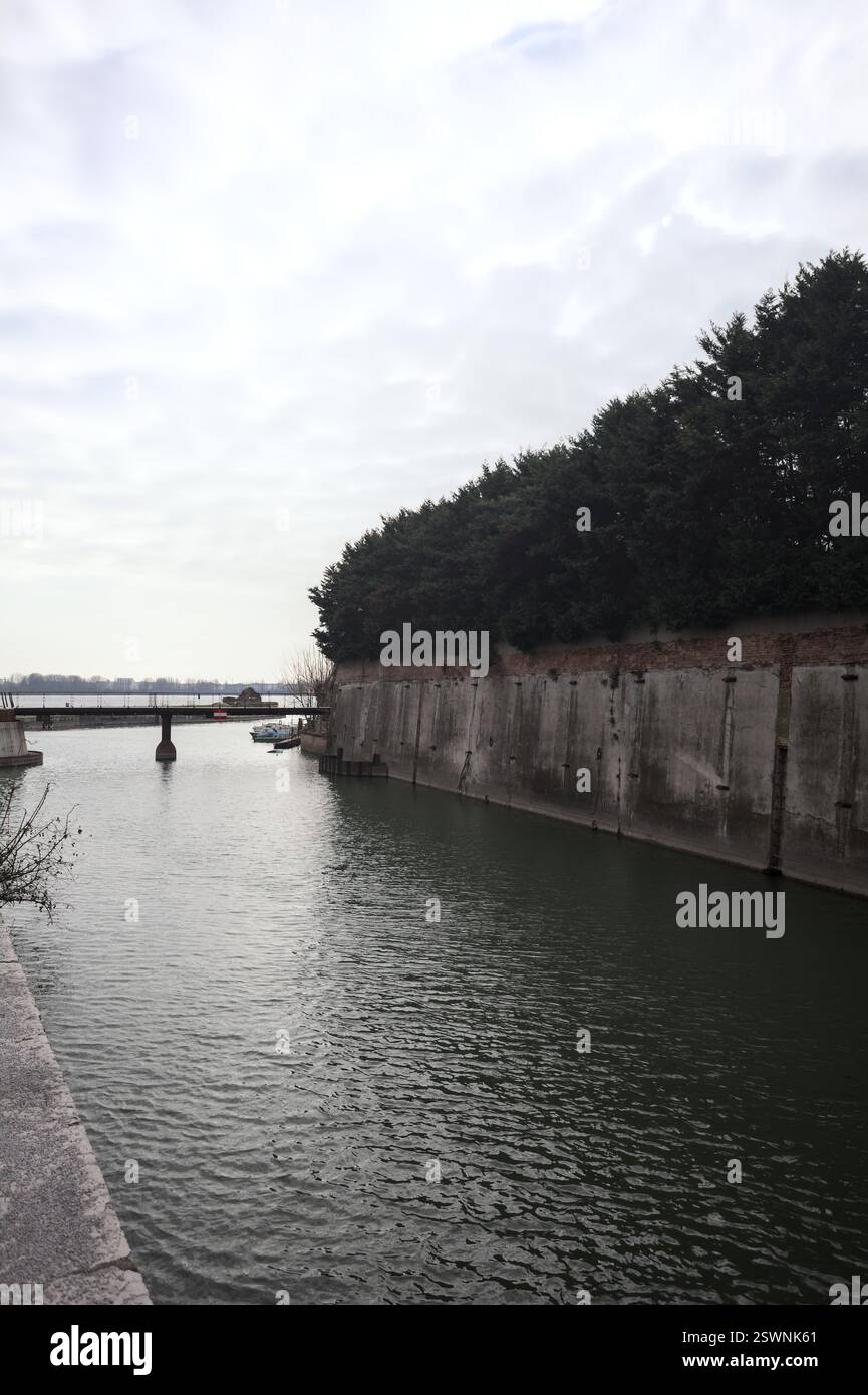 Stream of water bordered by concrete walls with a bridge afar and a ...