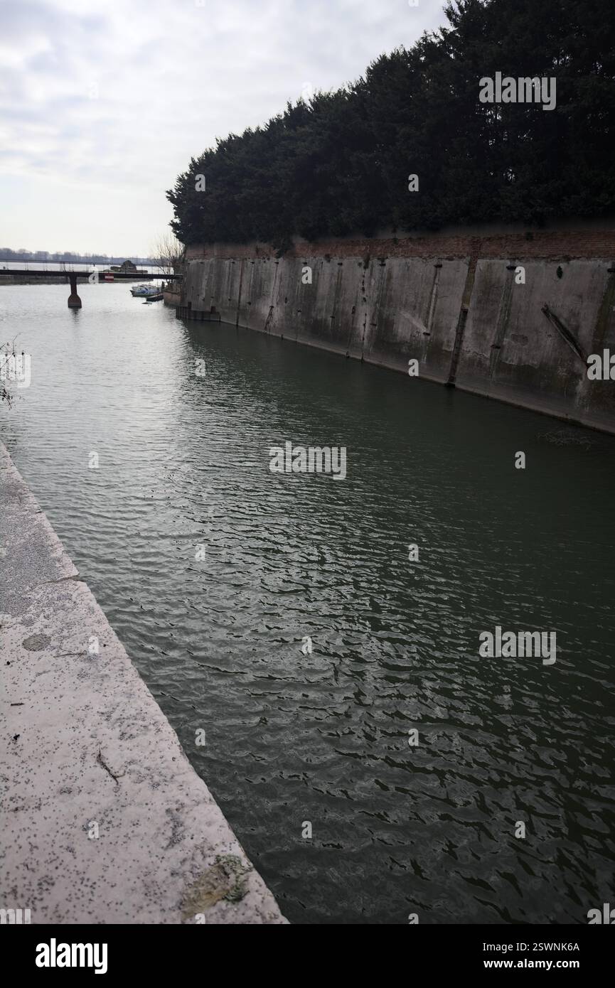 Stream of water bordered by concrete walls with a bridge afar and a ...