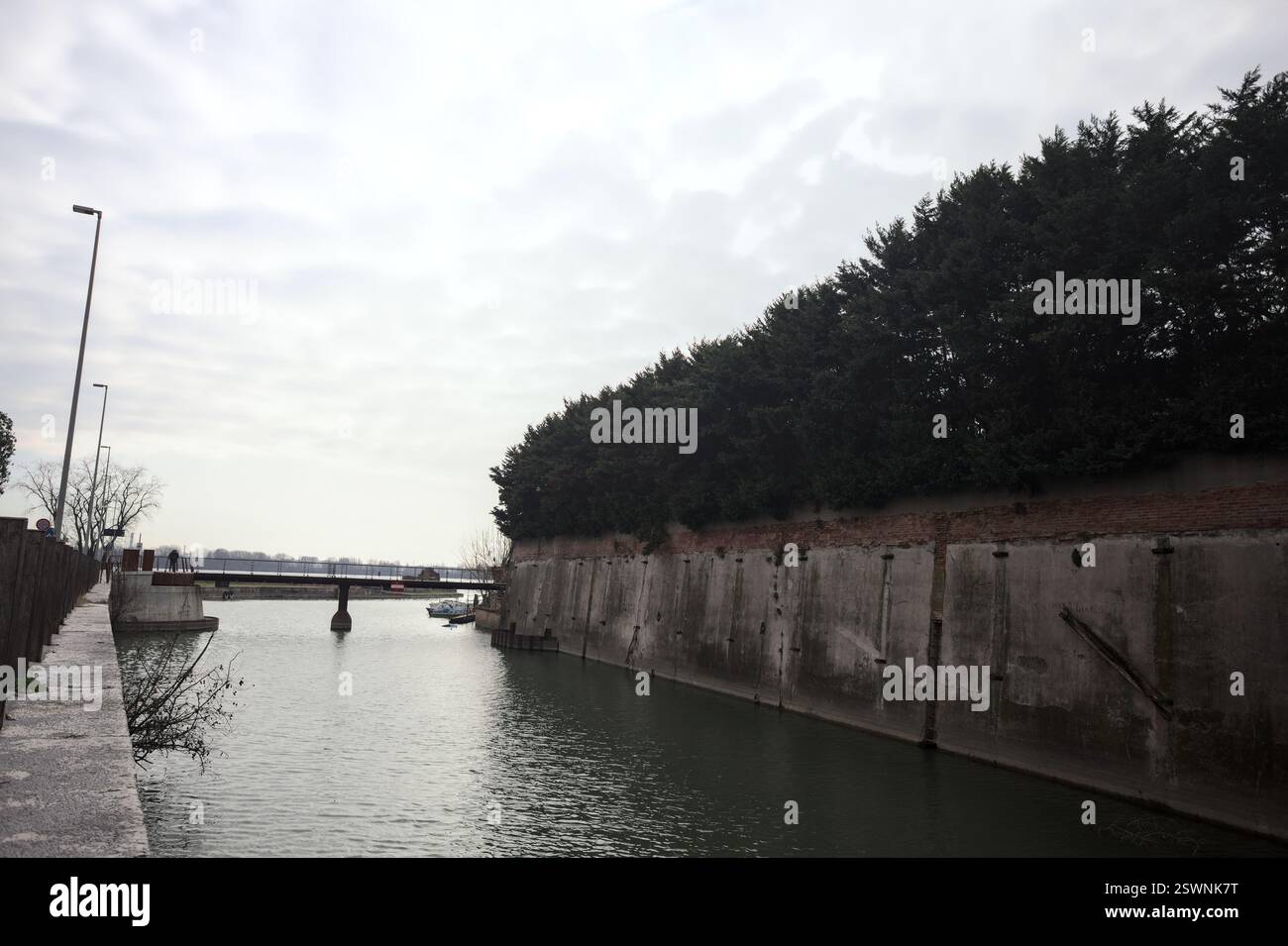 Stream of water bordered by concrete walls with a bridge afar and a ...