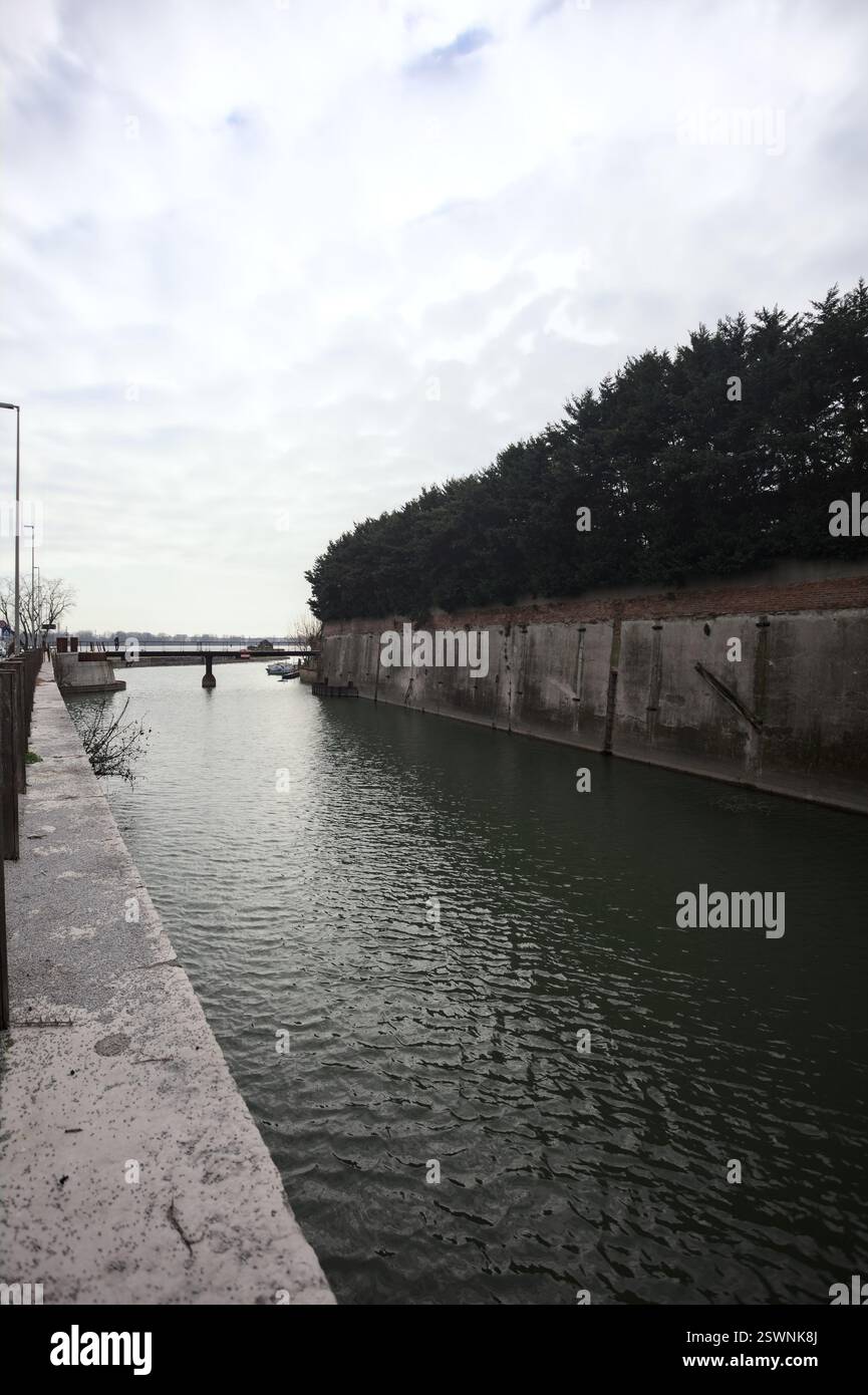 Stream of water bordered by concrete walls with a bridge afar and a ...