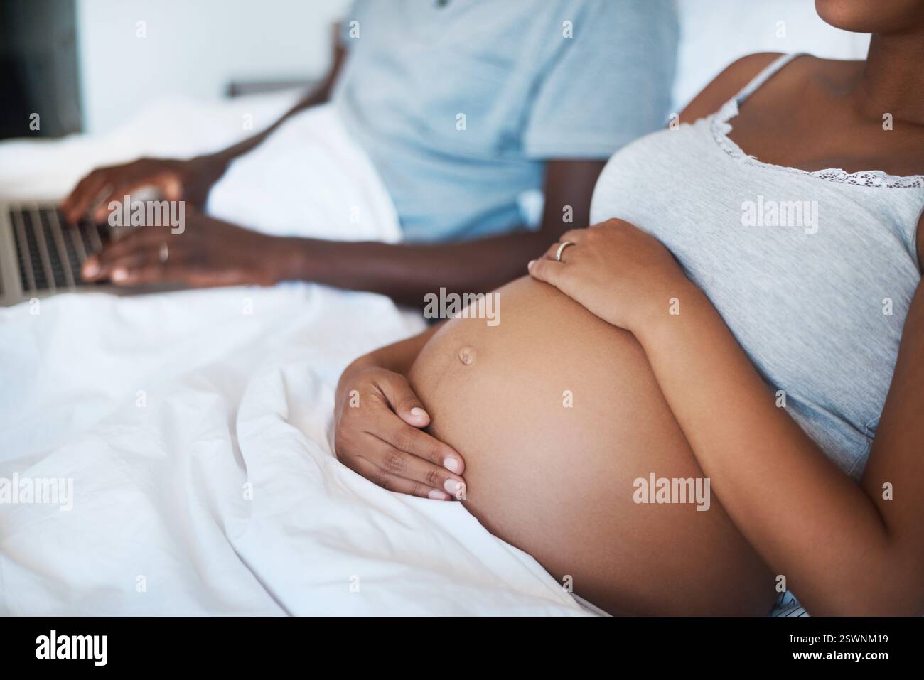 Hands, laptop and pregnancy with couple in bedroom together for ...