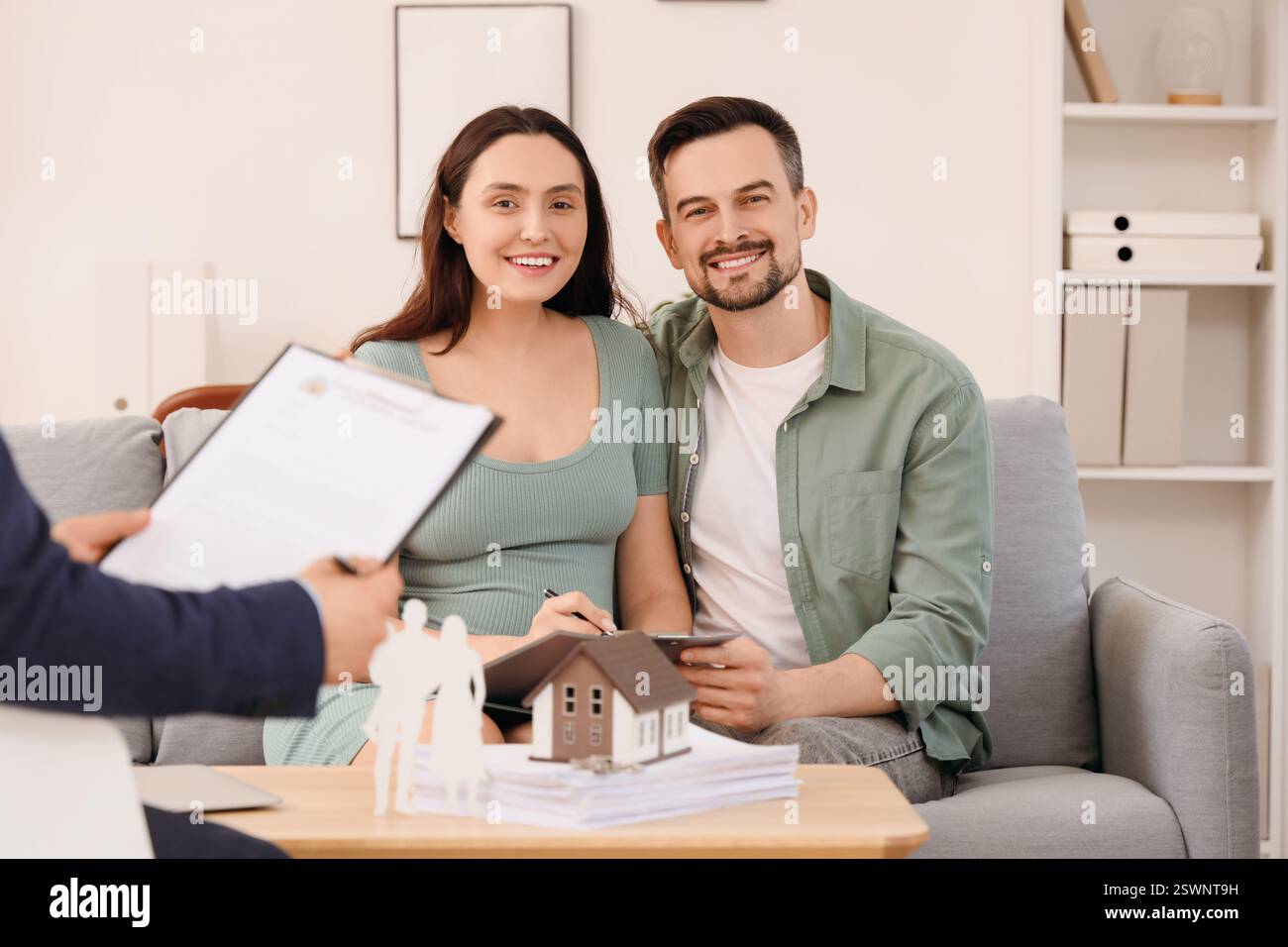 Young couple filling out house rental agreement at realtor's office ...