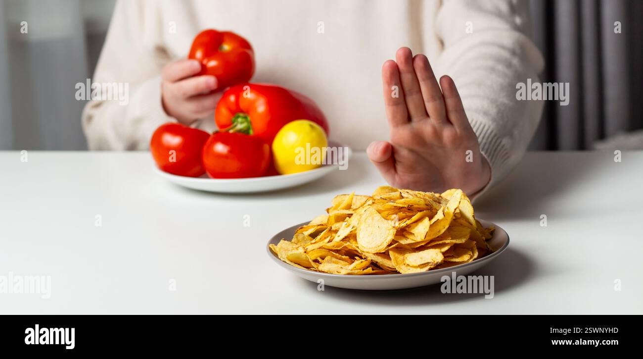 Woman saying "NO" to chips. Hand sign to refuse junk food. Choosing ...