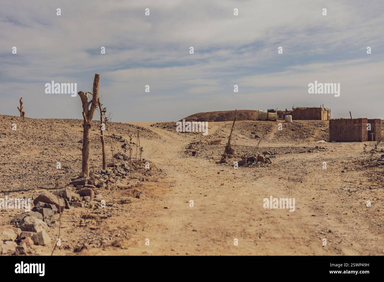 Pathway leading to a group of precarious houses in a desolate desert ...