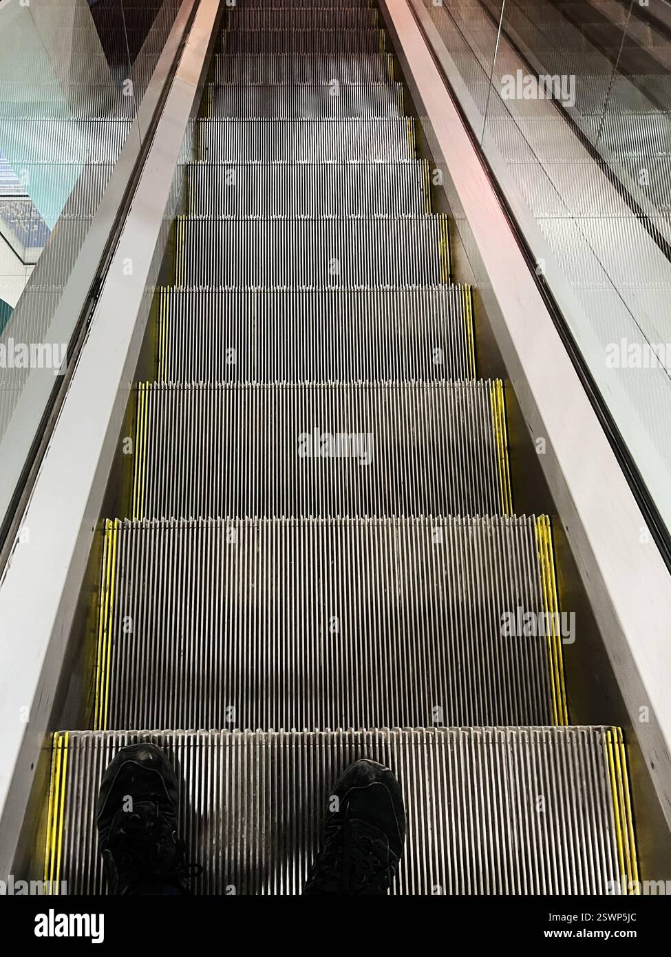 Detailed view of metallic escalator steps descending with reflections ...