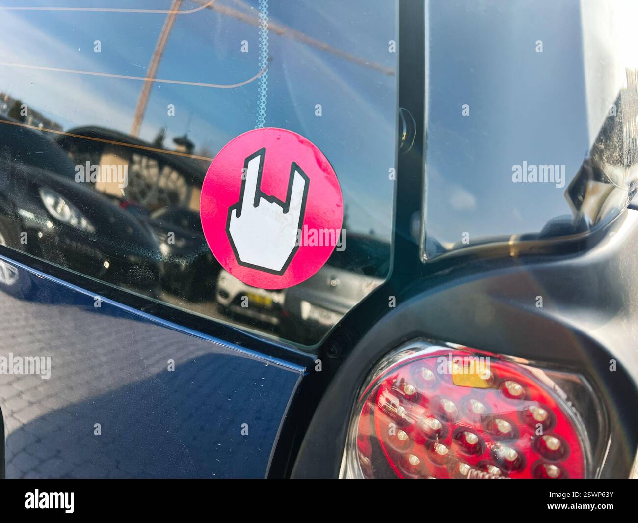 Photo of a car window with a rock hand gesture sticker on the rear side ...