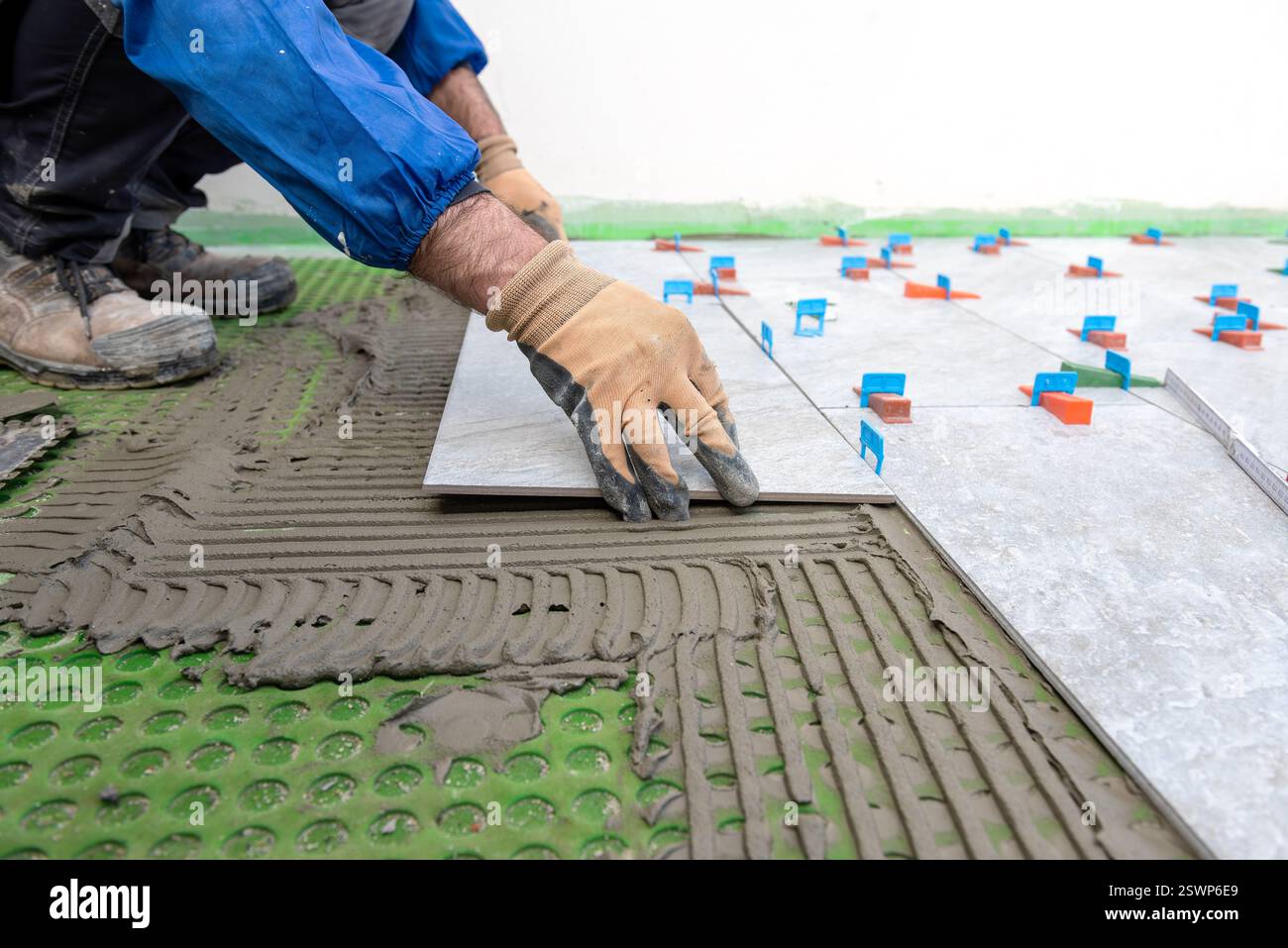 Bricklayer tiler places tiles for a new floor on cement glue ...
