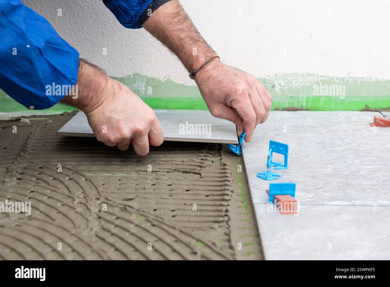 Bricklayer tiler places tiles for a new floor on cement glue ...