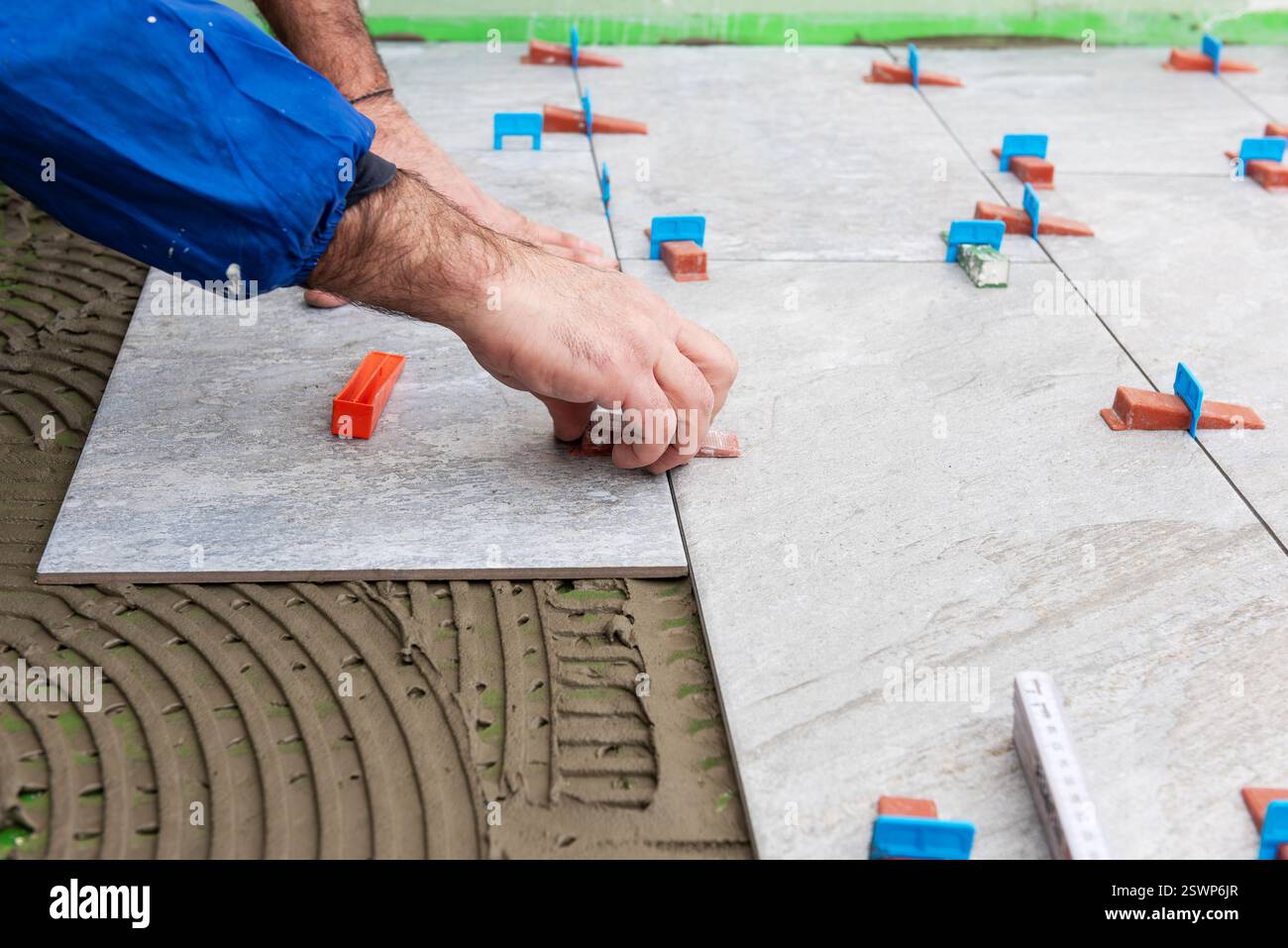 Bricklayer tiler installs tiles using leveling spacers. Construction ...