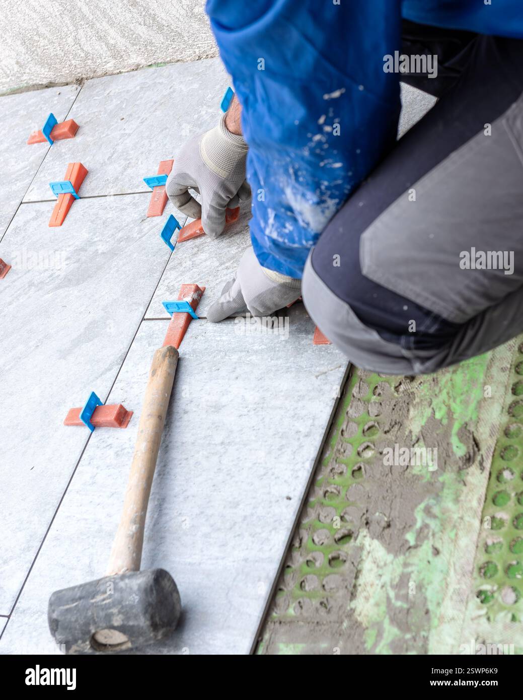 Bricklayer tiler installs tiles using leveling spacers. Construction ...