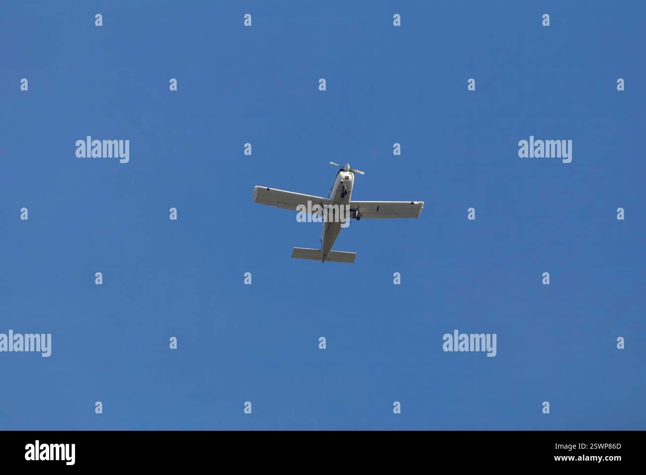 A light aircraft photographed from below against a clear blue sky ...