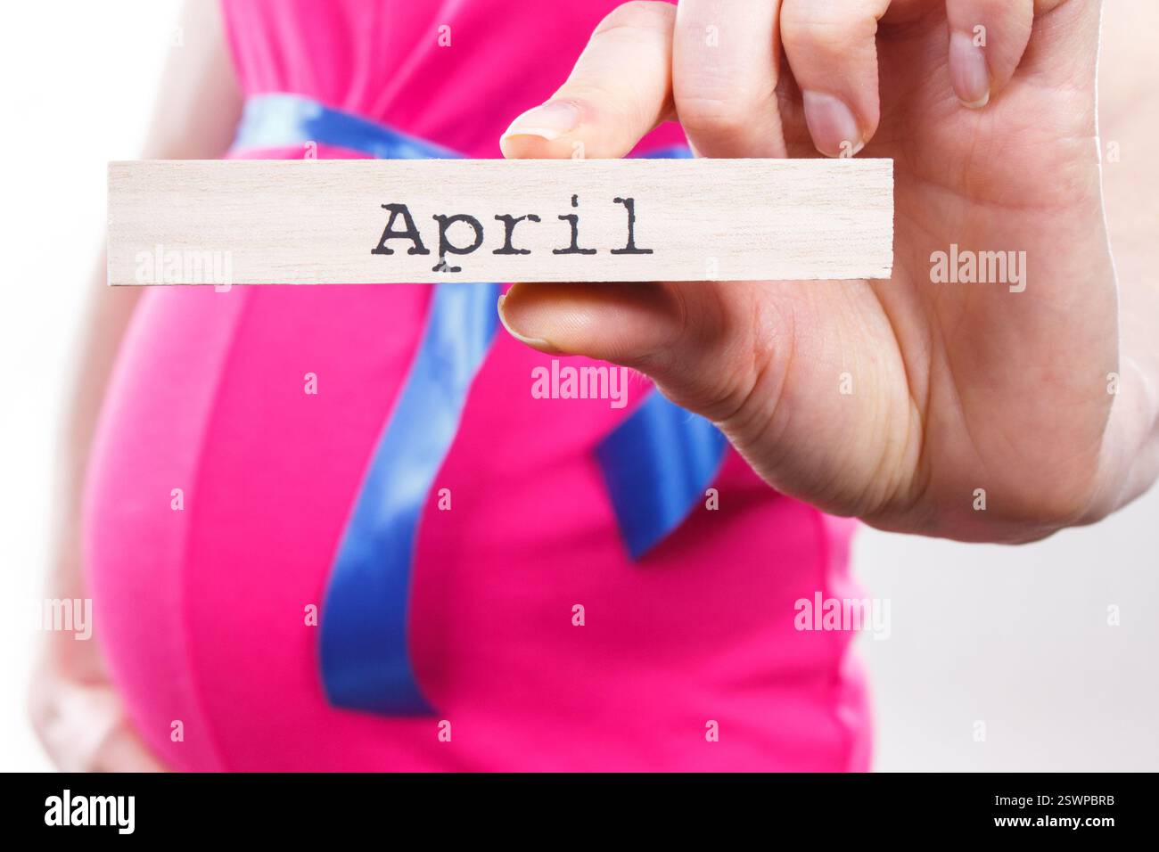 Pregnant woman in pink dress with blue ribbon showing word april ...