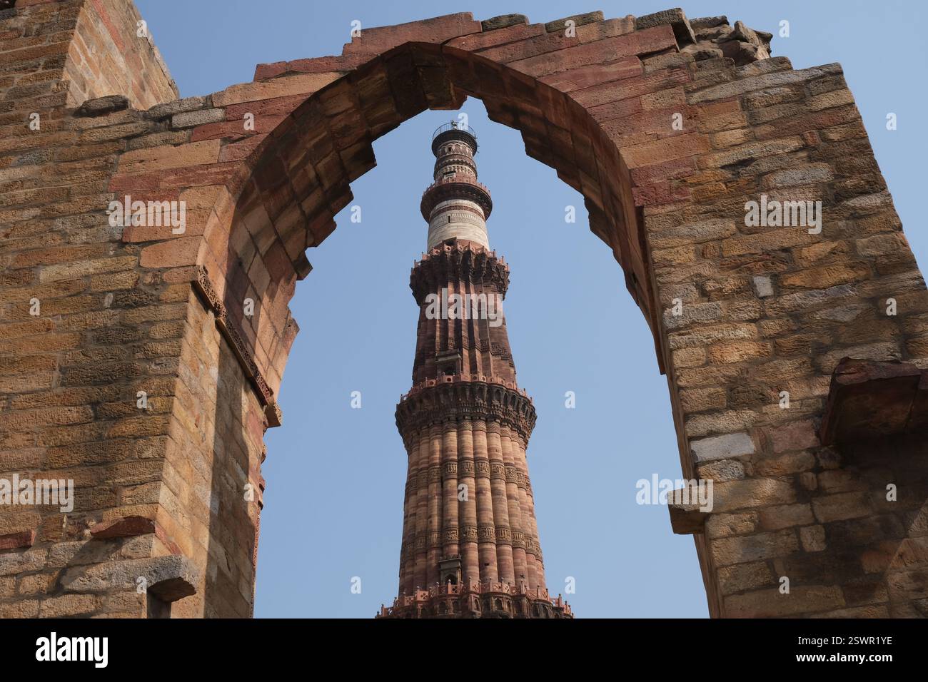 The Qutub Minar minaret seen through a ruined archway at this popular ...