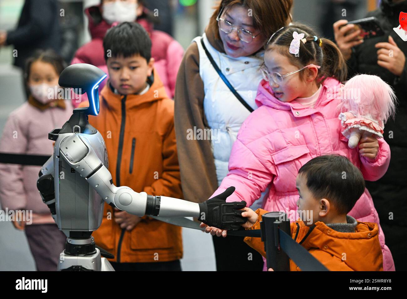 NANJING, CHINA - FEBRUARY 22, 2025 - Visitors shake hands with a robot ...