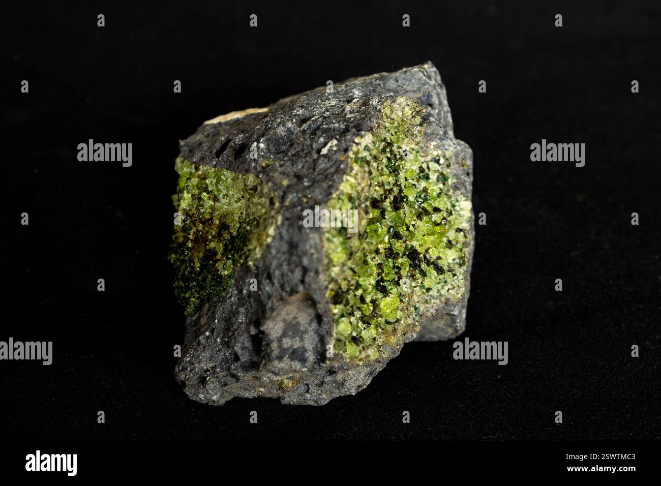 A xenolith of vibrant green peridot crystals with a few dark Olivine ...