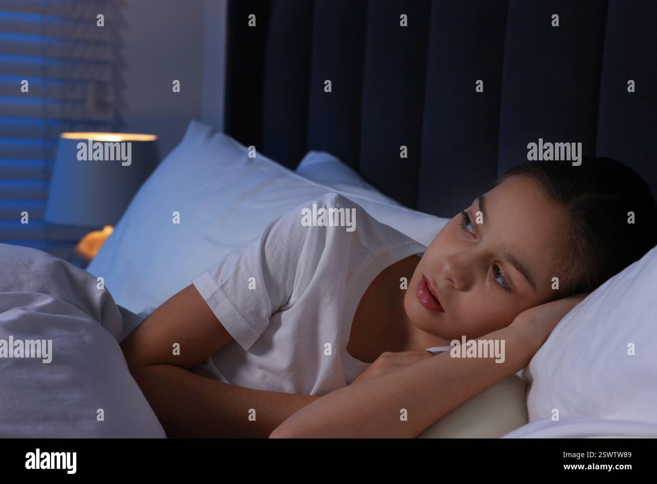 Scared girl lying in bed at night Stock Photo - Alamy