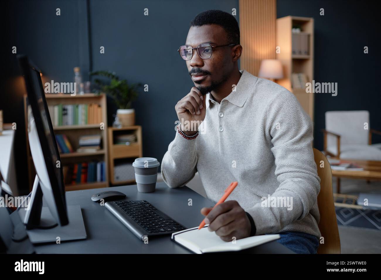 Puzzled adult Black man with glasses looking at computer screen ...