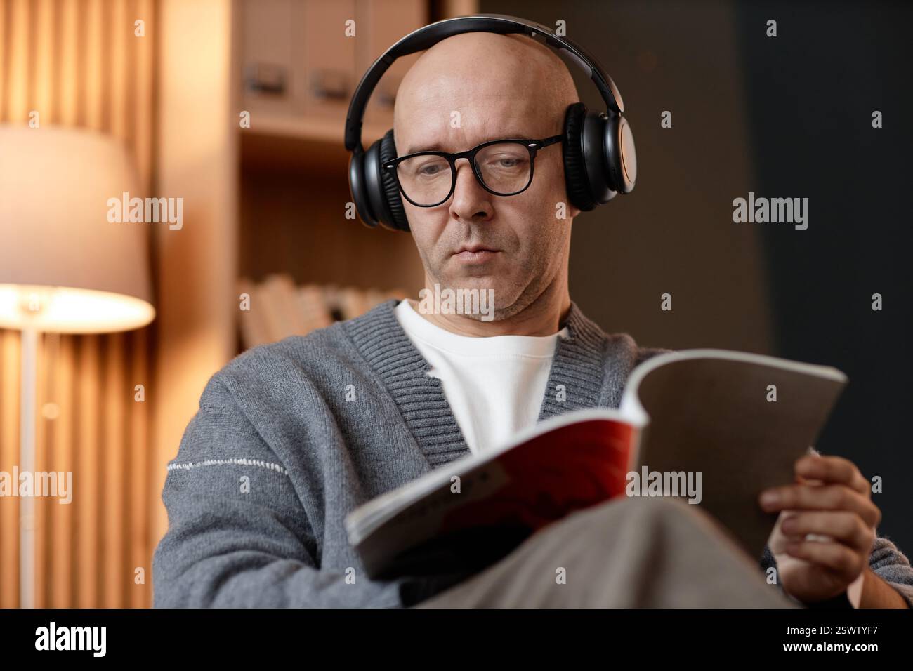 Chest up shot of bald middle aged man with glasses listening to music ...