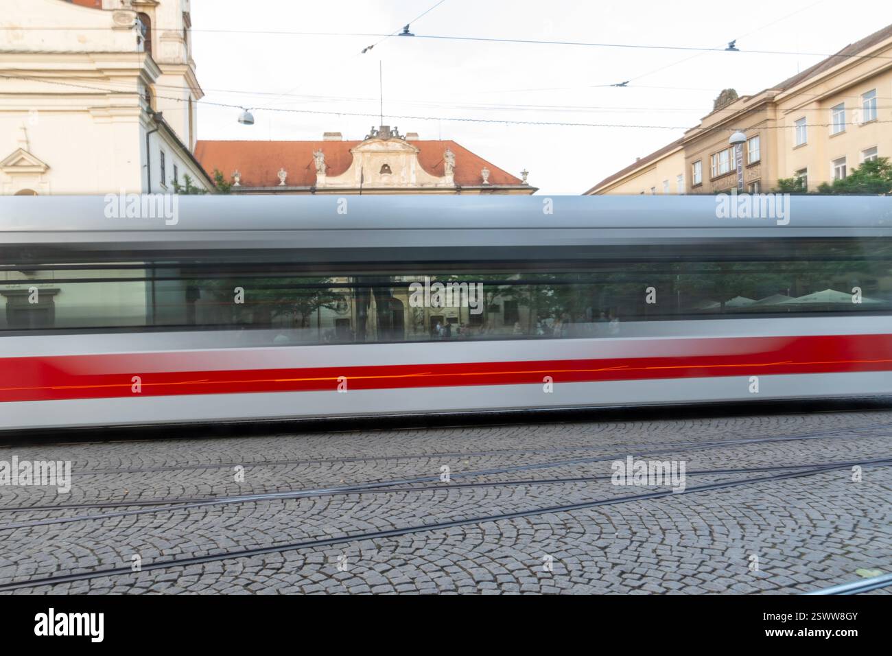 A modern tram in motion speeds through a historic European city ...